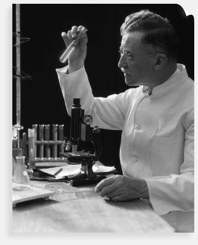 1920s 1930s 1940s scientist lab technician in white coat looking at ...